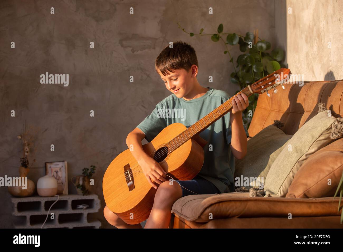 Preteen child, boy, learning how to play acoustic guitar at home, sunny ...