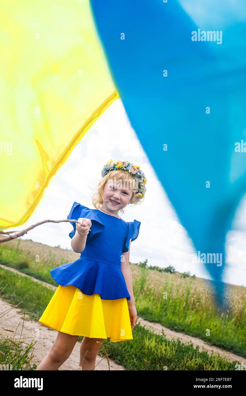 flag of Ukraine is on the shoulders of a little Ukrainian girl. Happy ...