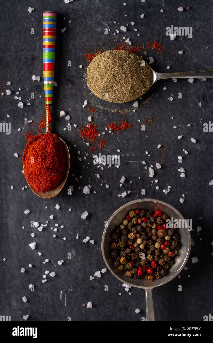 Three old spoons with peppercorn, ground pepper and red paprika powder ...
