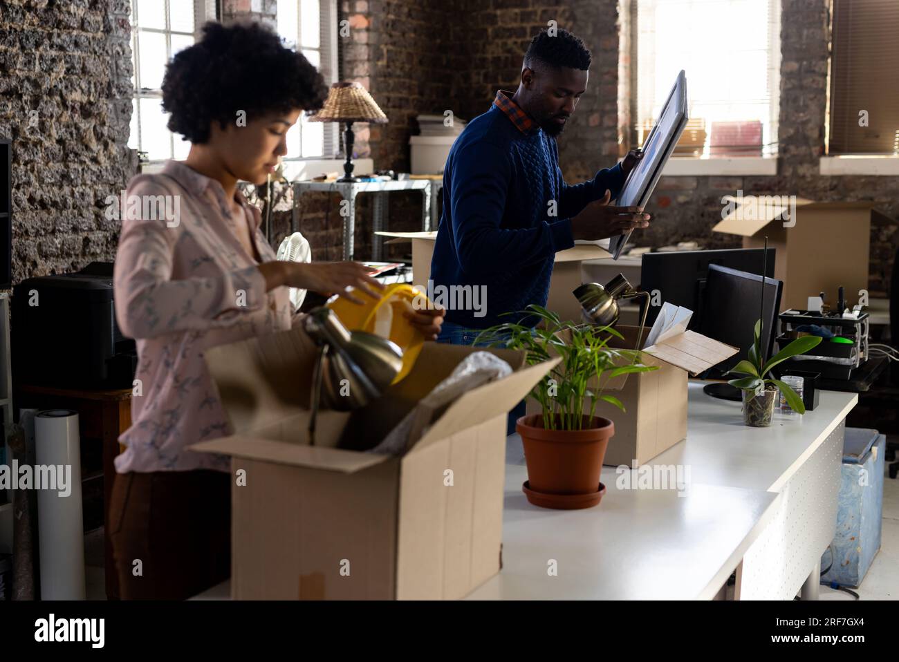 Diverse male and female colleagues unpacking boxes, moving into office ...