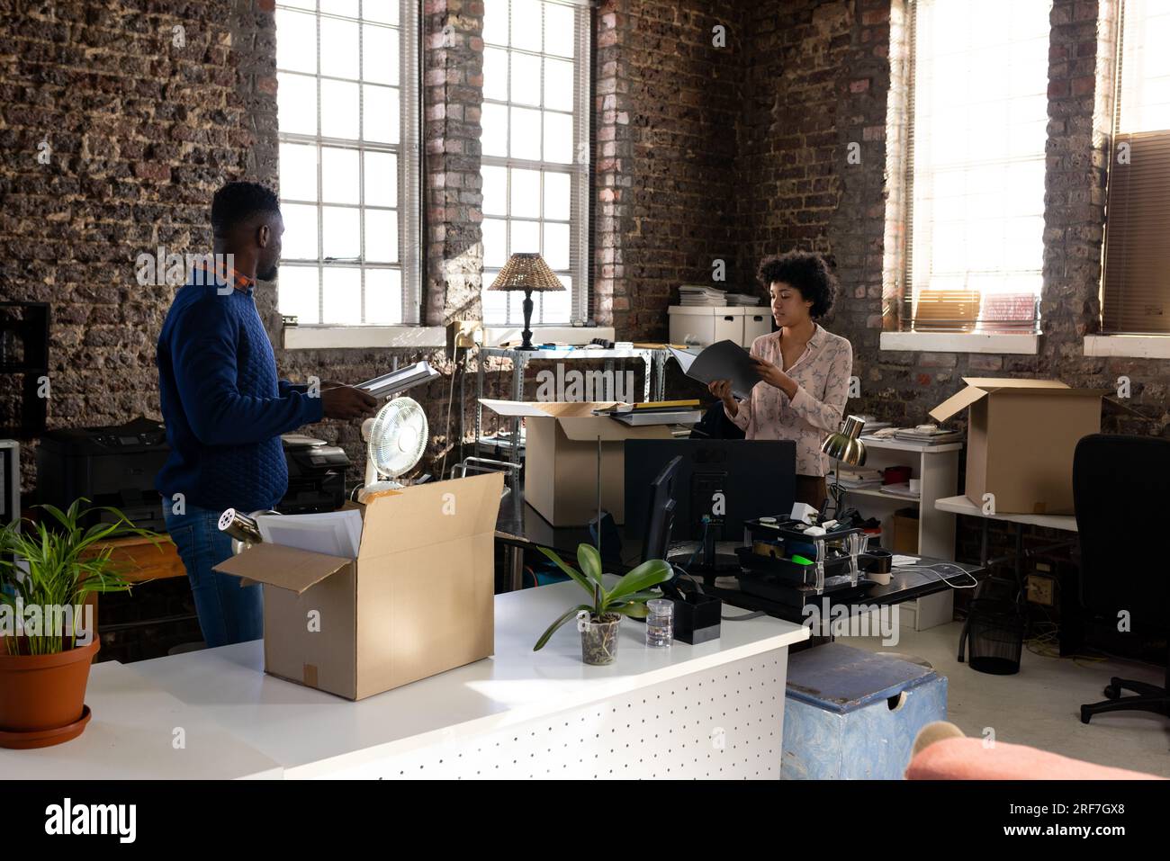 Diverse male and female colleagues unpacking documents from boxes ...