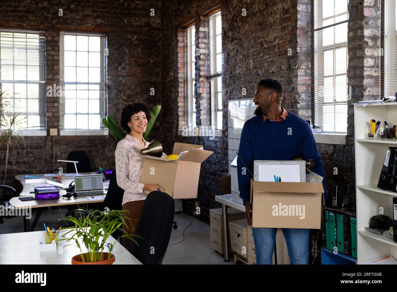Happy diverse male and female colleagues carrying packing boxes, moving ...