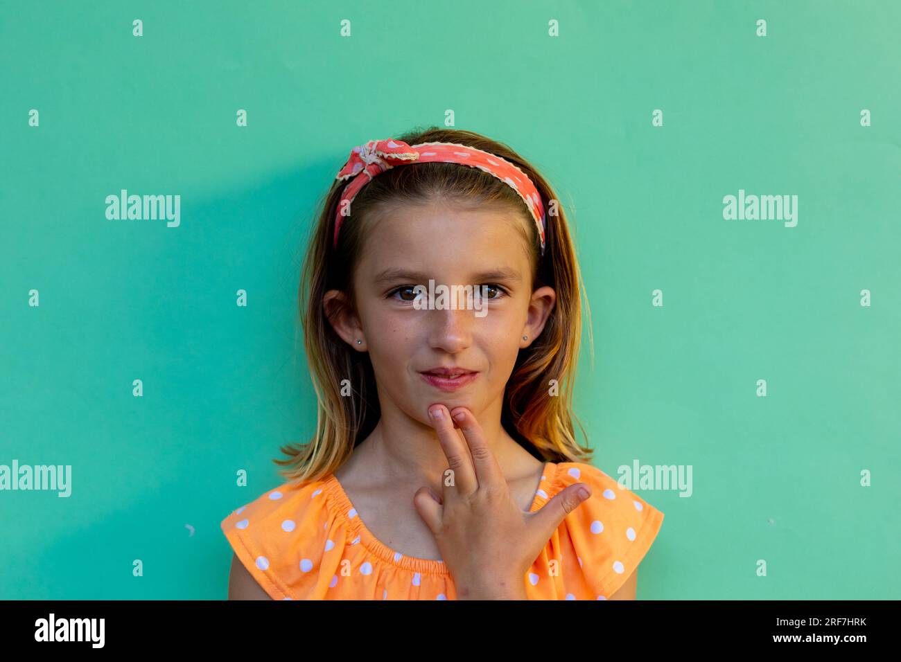 Happy caucasian schoolgirl doing sign language gesture over blue ...