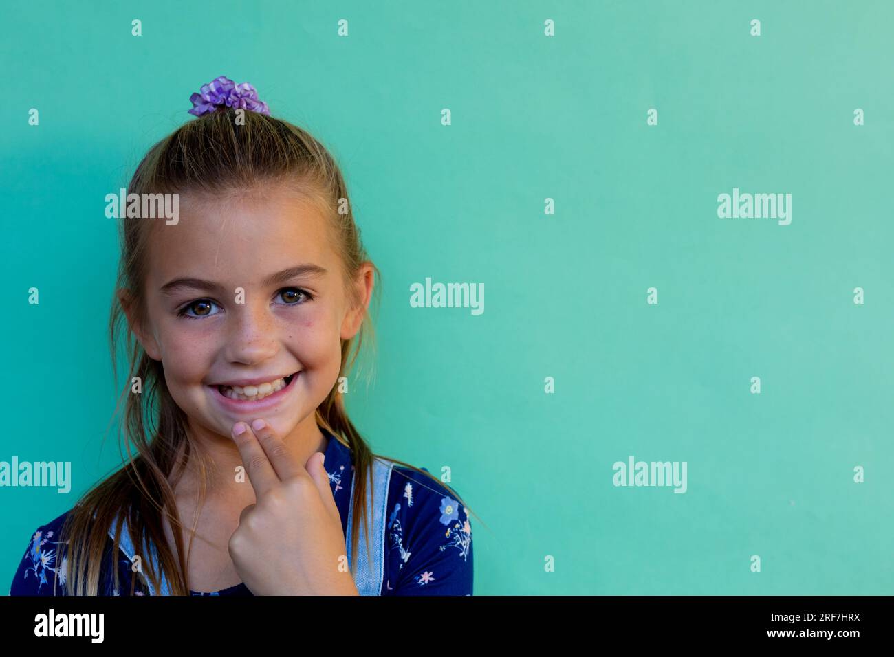 Caucasian schoolgirl with ponytail doing sign language gesture at ...