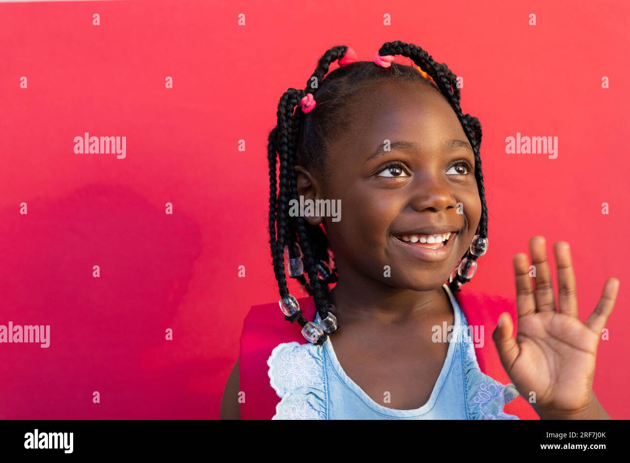 Happy african american schoolgirl waving hand over pink background at ...