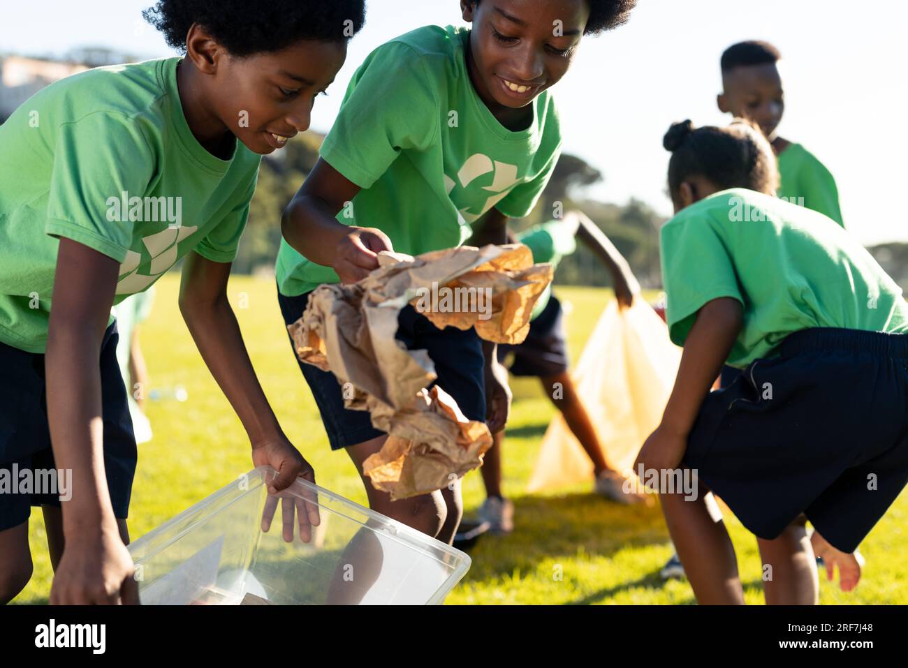 Happy diverse children collecting plastic waste in sunny elementary ...