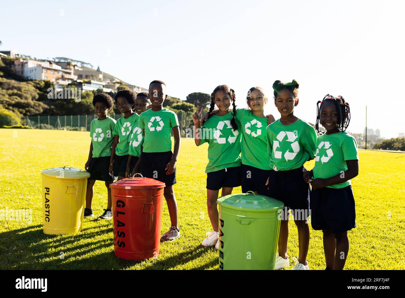 Portrait of happy diverse children collecting recycling embracing in ...