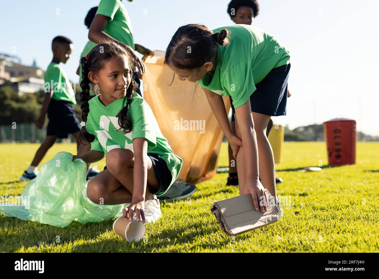 Happy diverse children collecting plastic waste in sunny elementary ...