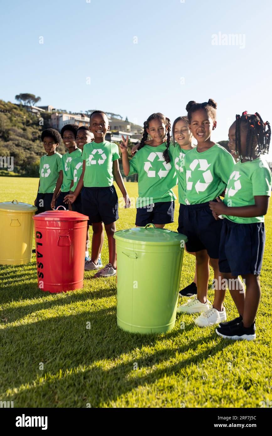 Portrait of happy diverse children collecting recycling embracing in ...