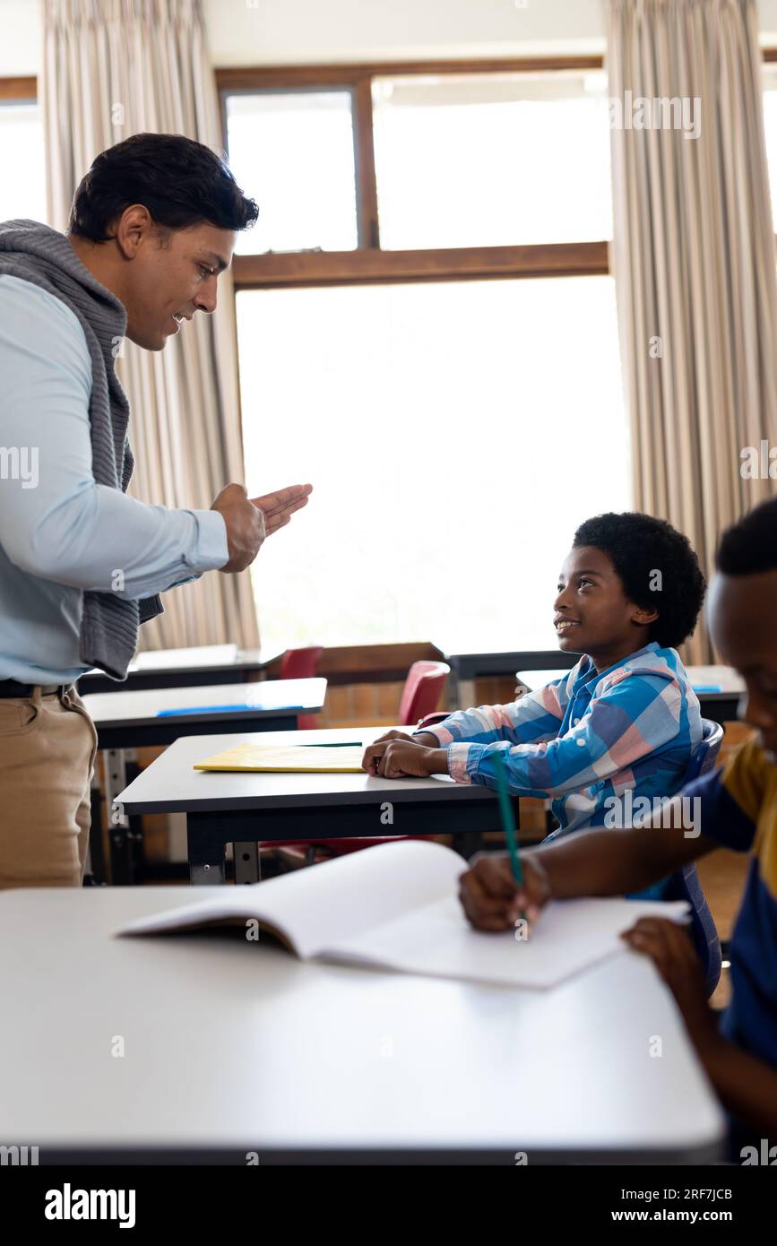 Diverse male teacher teaching school boy using sign language in class ...