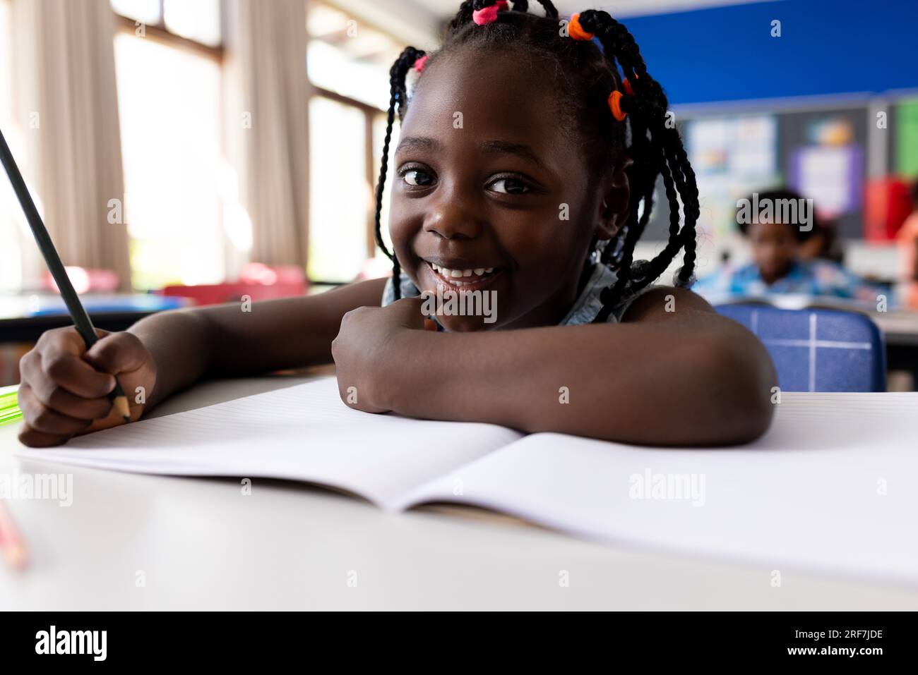 Portrait of african american girl writing in classroom at elementary ...