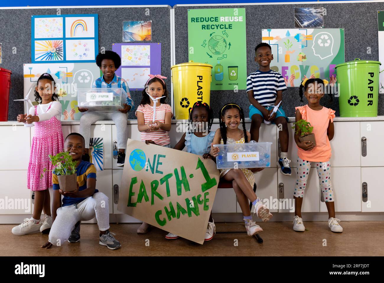 Portrait of happy diverse children with ecology items and plants in ...