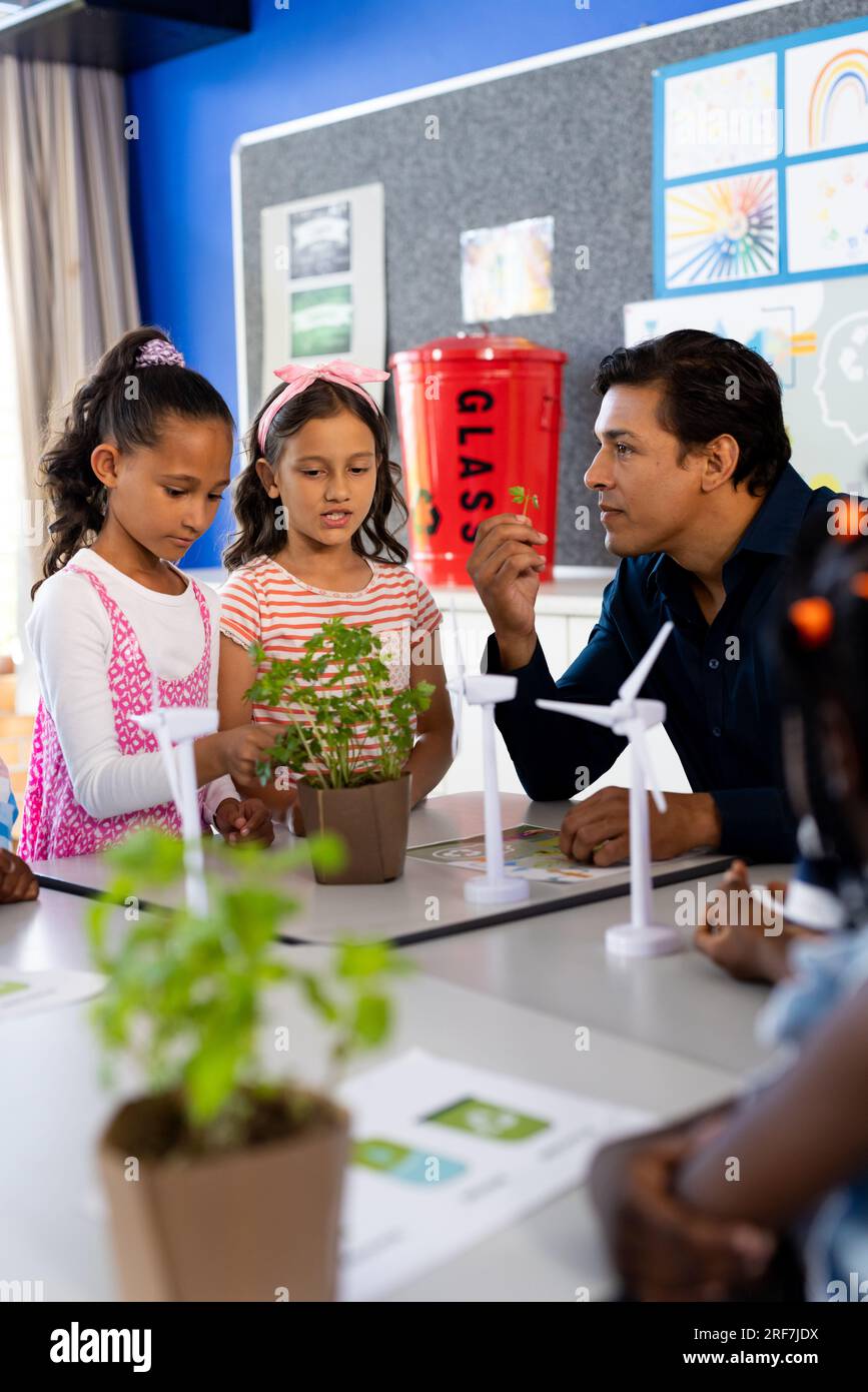 Happy diverse male teacher and children with ecology items in class at ...