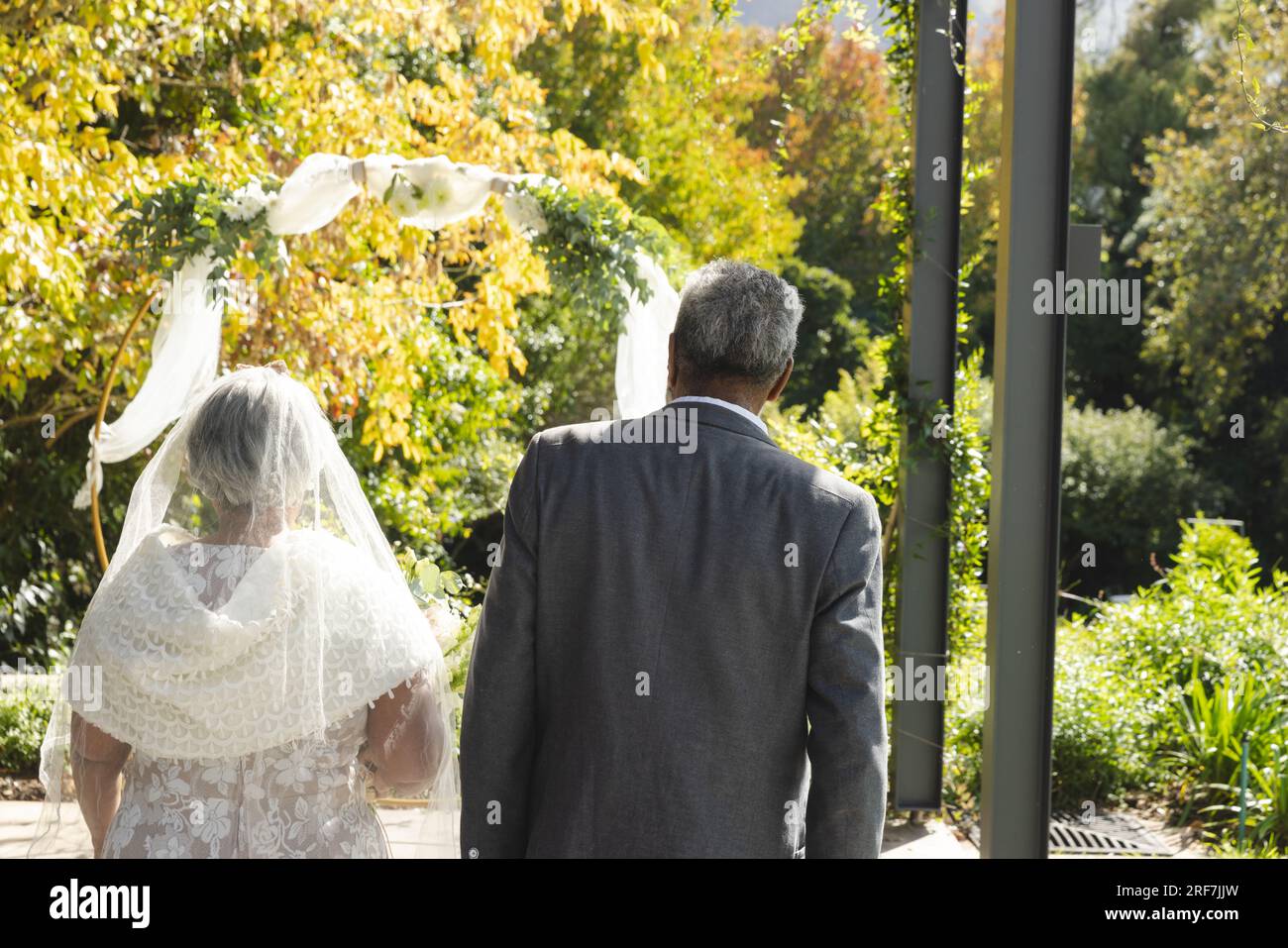 Rear view of happy senior biracial bride and groom holding hands at ...