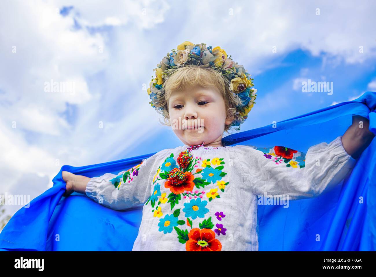 funny little girl peeks out from under flag. happy child carries yellow ...