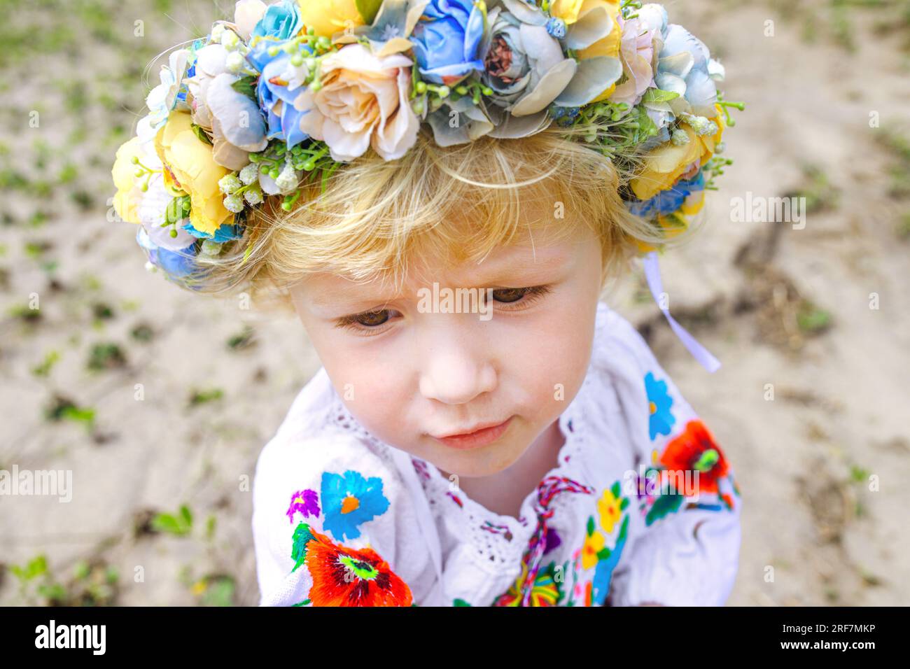 A sad Ukrainian girl in a wreath and embroidered shirt. The child is a ...