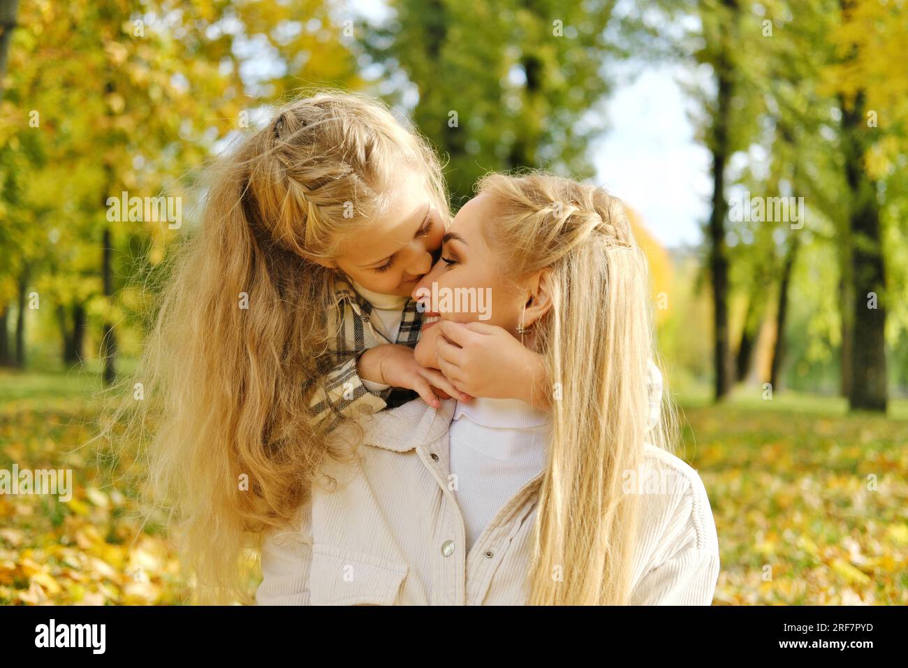 The family has fun in the park. The girl hugs her mother by the neck ...
