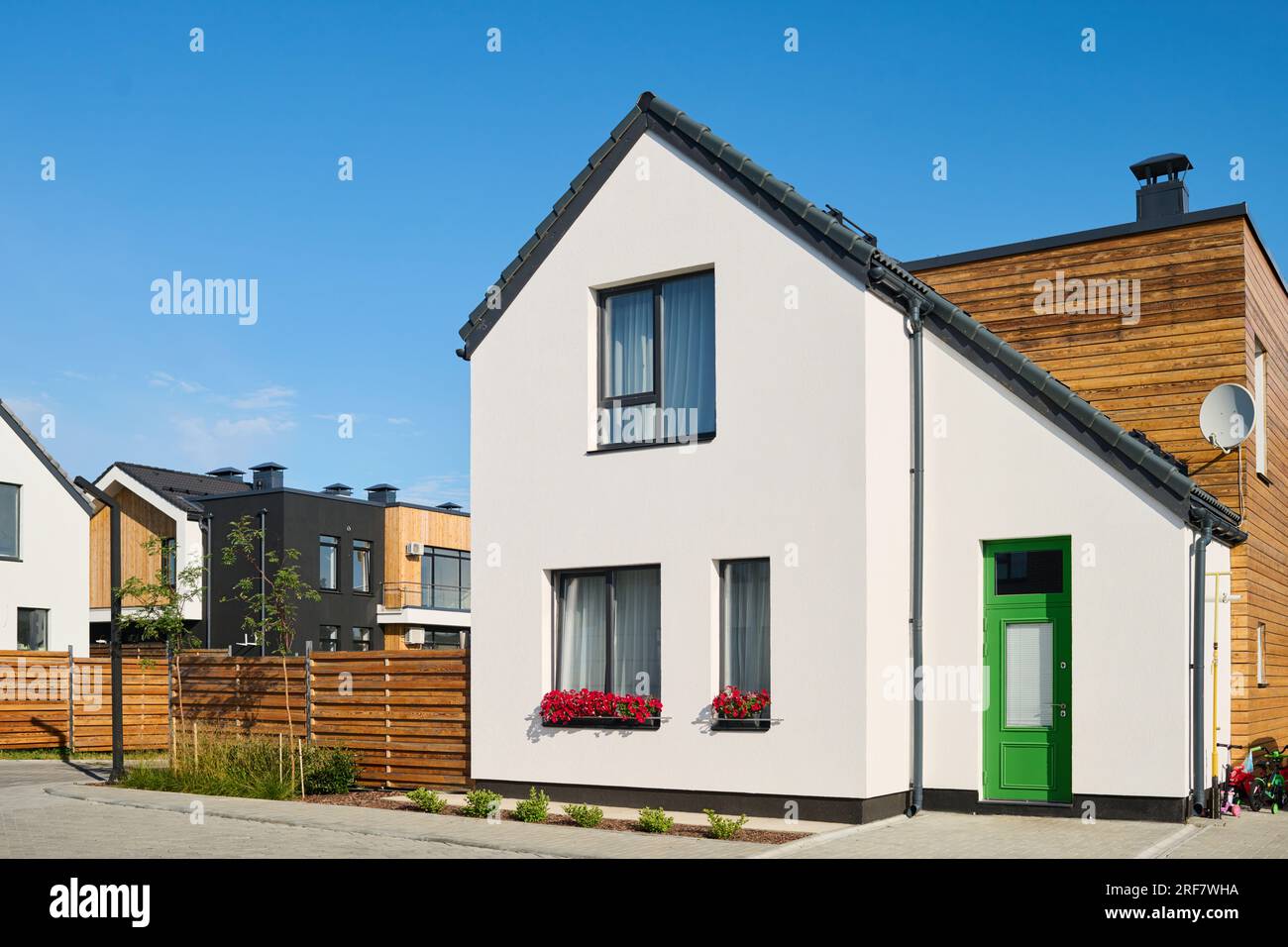 Exterior of small white brick cottage with closed green door and three ...
