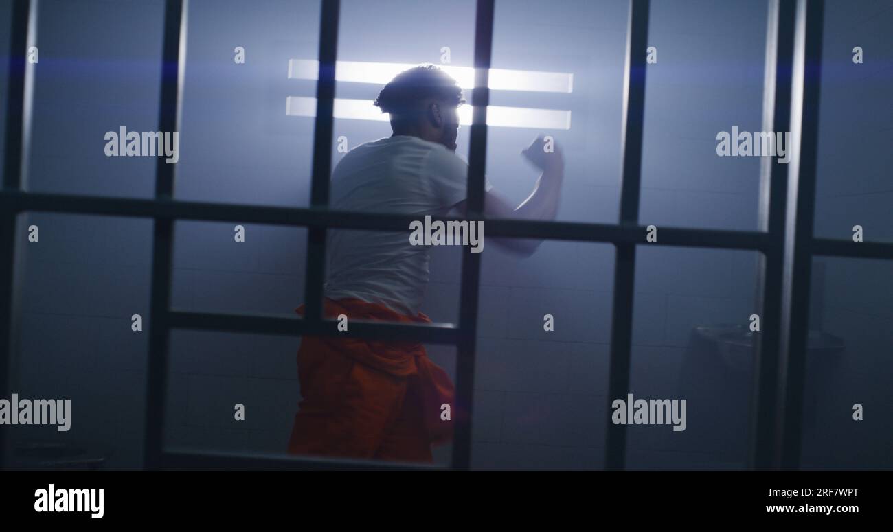 Male African American prisoner in orange uniform does shadow boxing in ...
