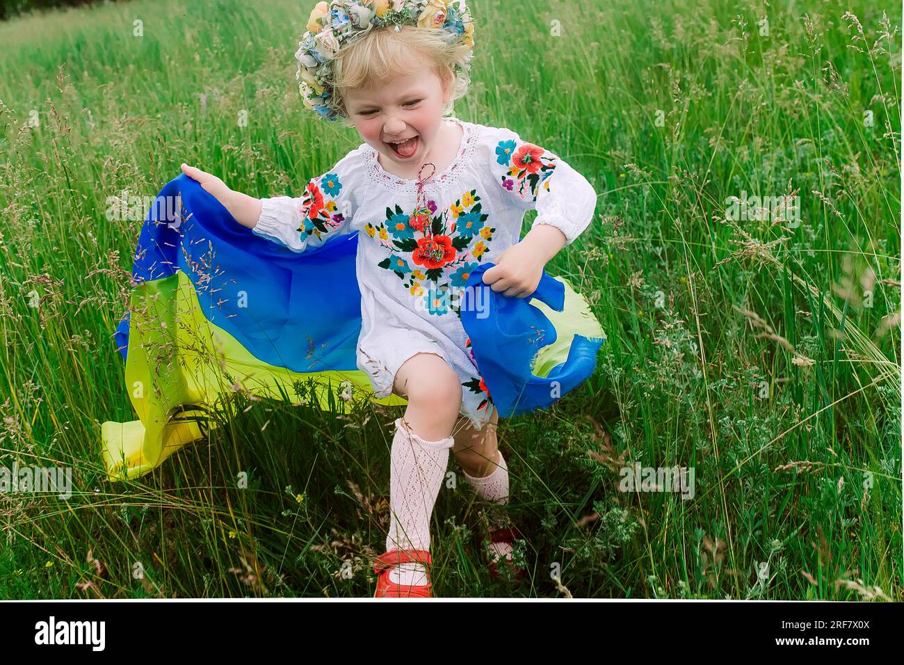 flag of Ukraine is on the shoulders of a little Ukrainian girl. Happy ...