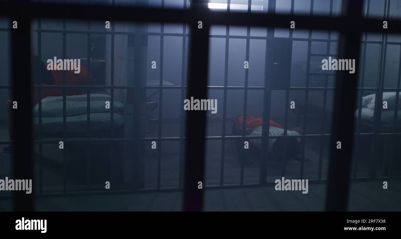 African American prisoner in orange uniform does push-ups and shadow ...