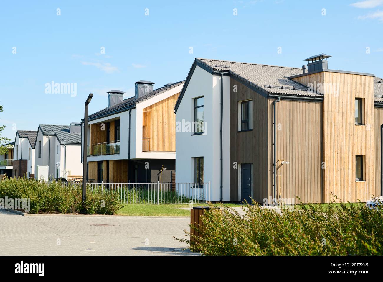 Two small houses with front yards with fencing and green bushes ...