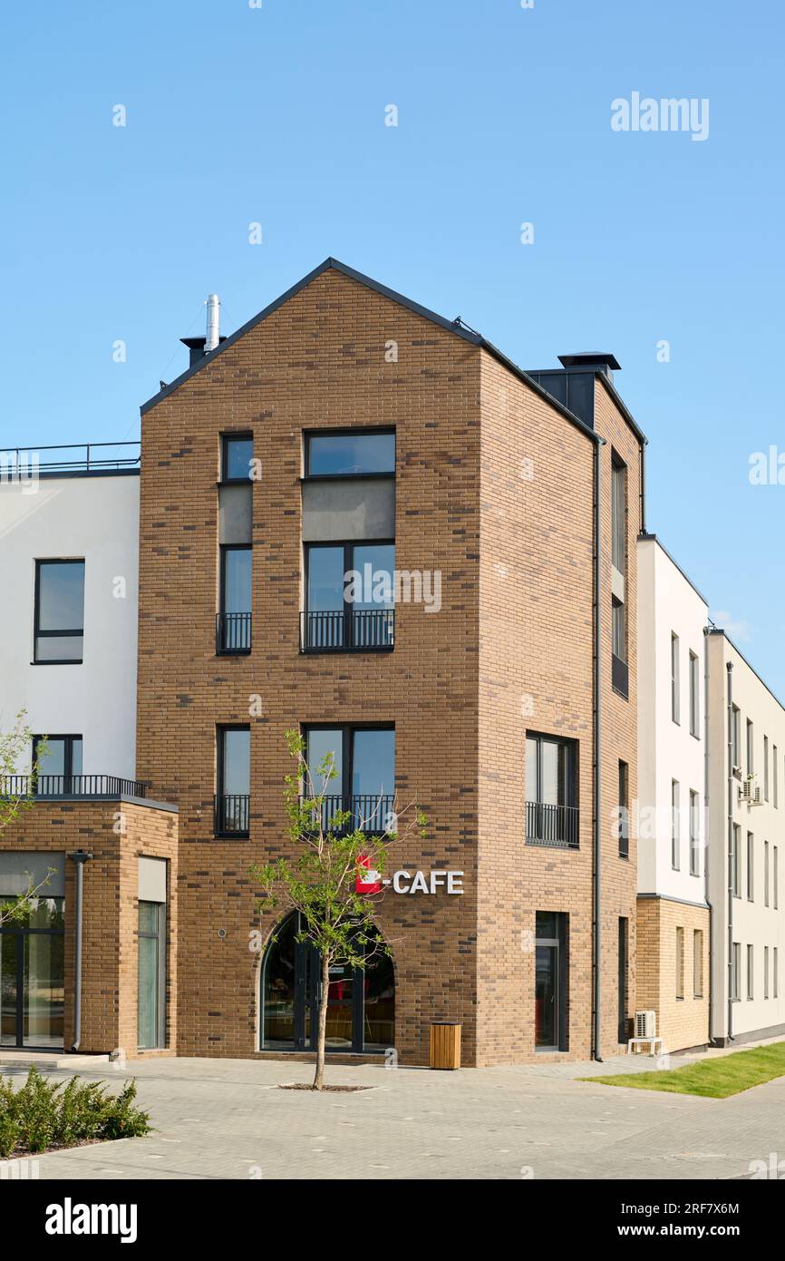 Corner of large three storey block of flats with small cafe on front ...