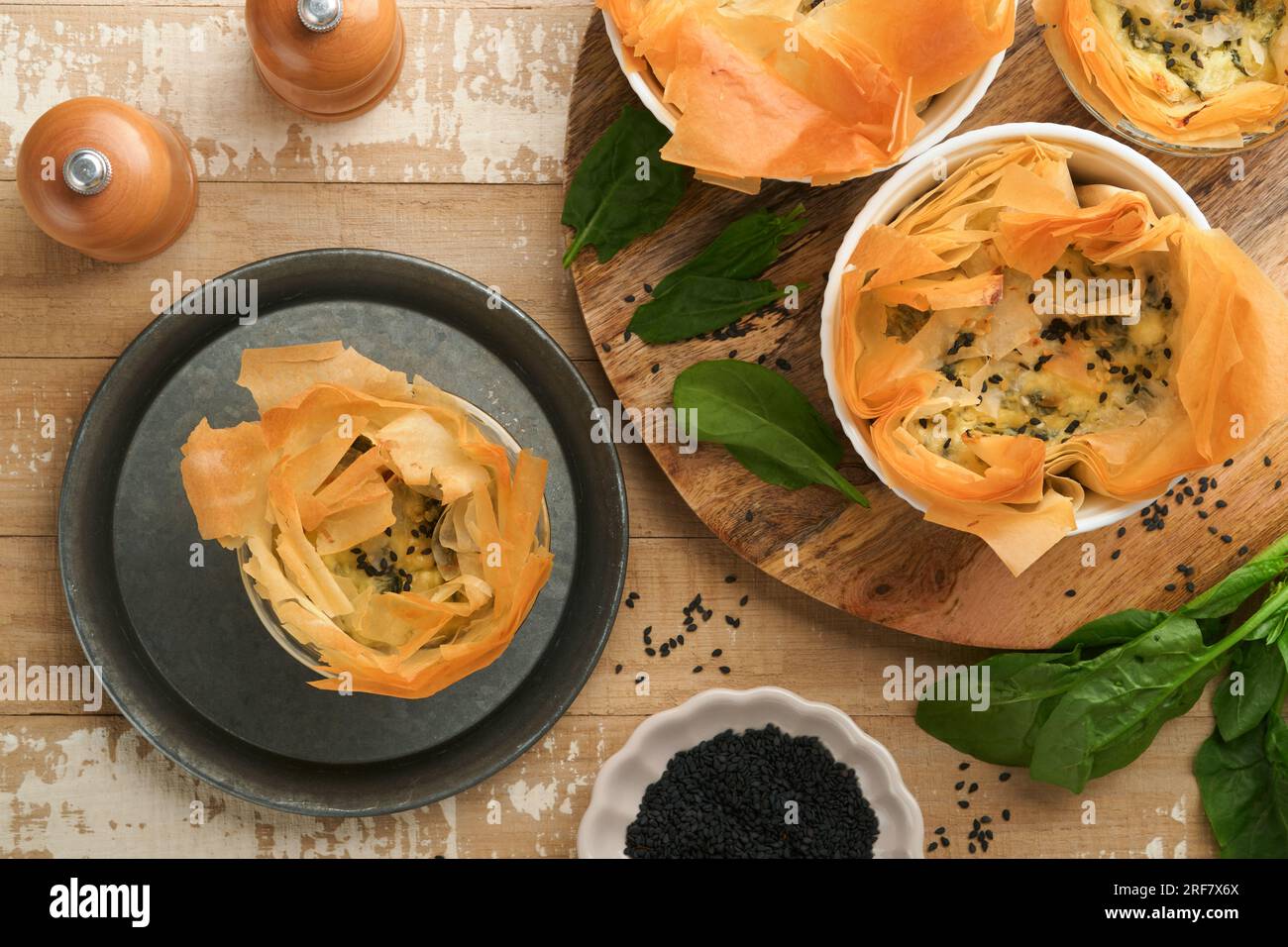 Filo pies with soft feta cheese and spinach in ceramic molds on old ...