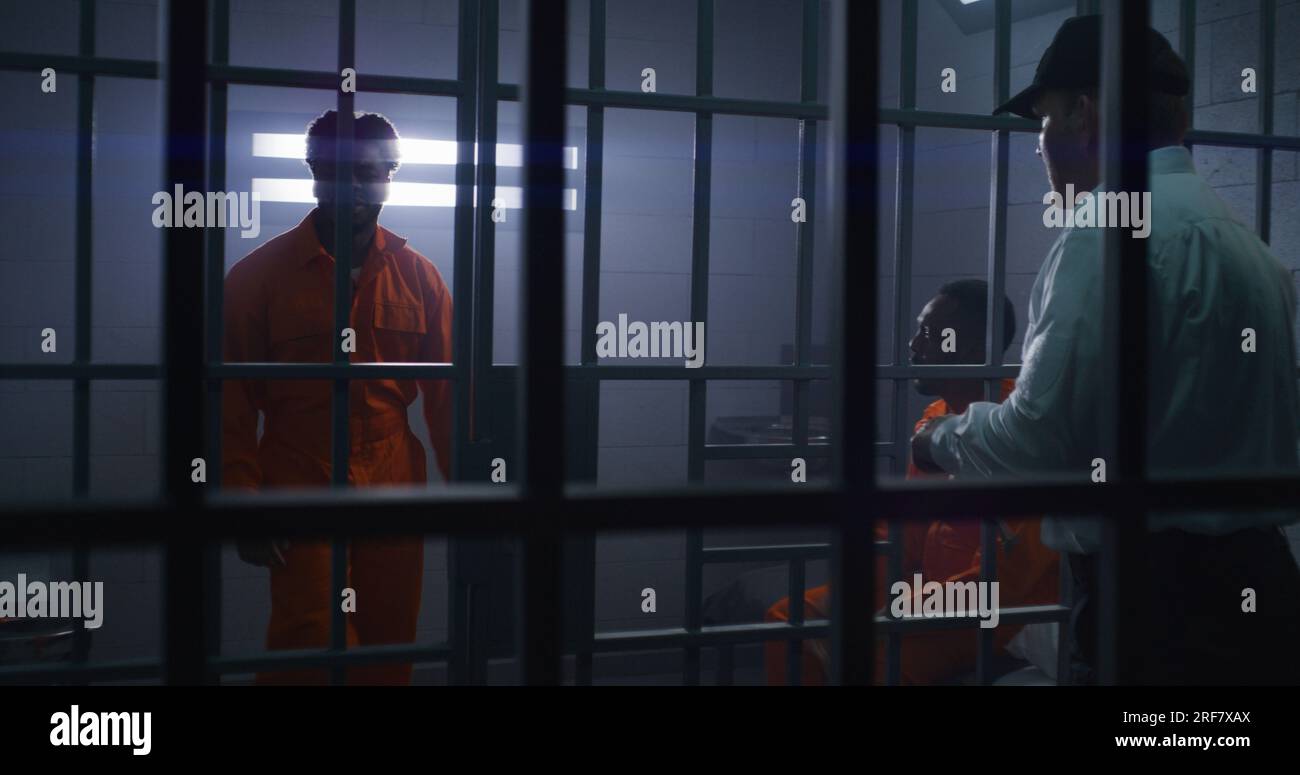 Prison employee puts on handcuffs on guilty inmate in orange uniform ...