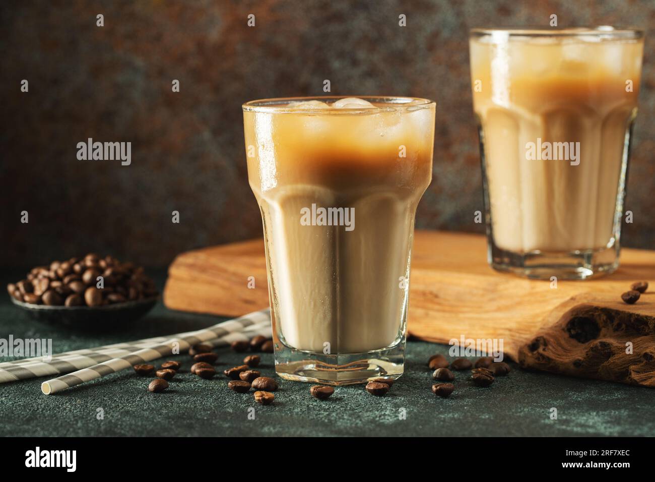 Ice coffee in a tall glass with cream poured over, ice cubes and beans ...