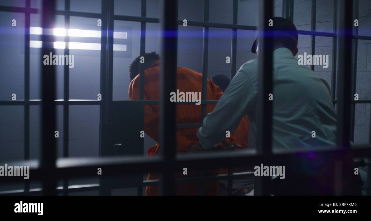 Prison employee puts on handcuffs on guilty inmate in orange uniform ...