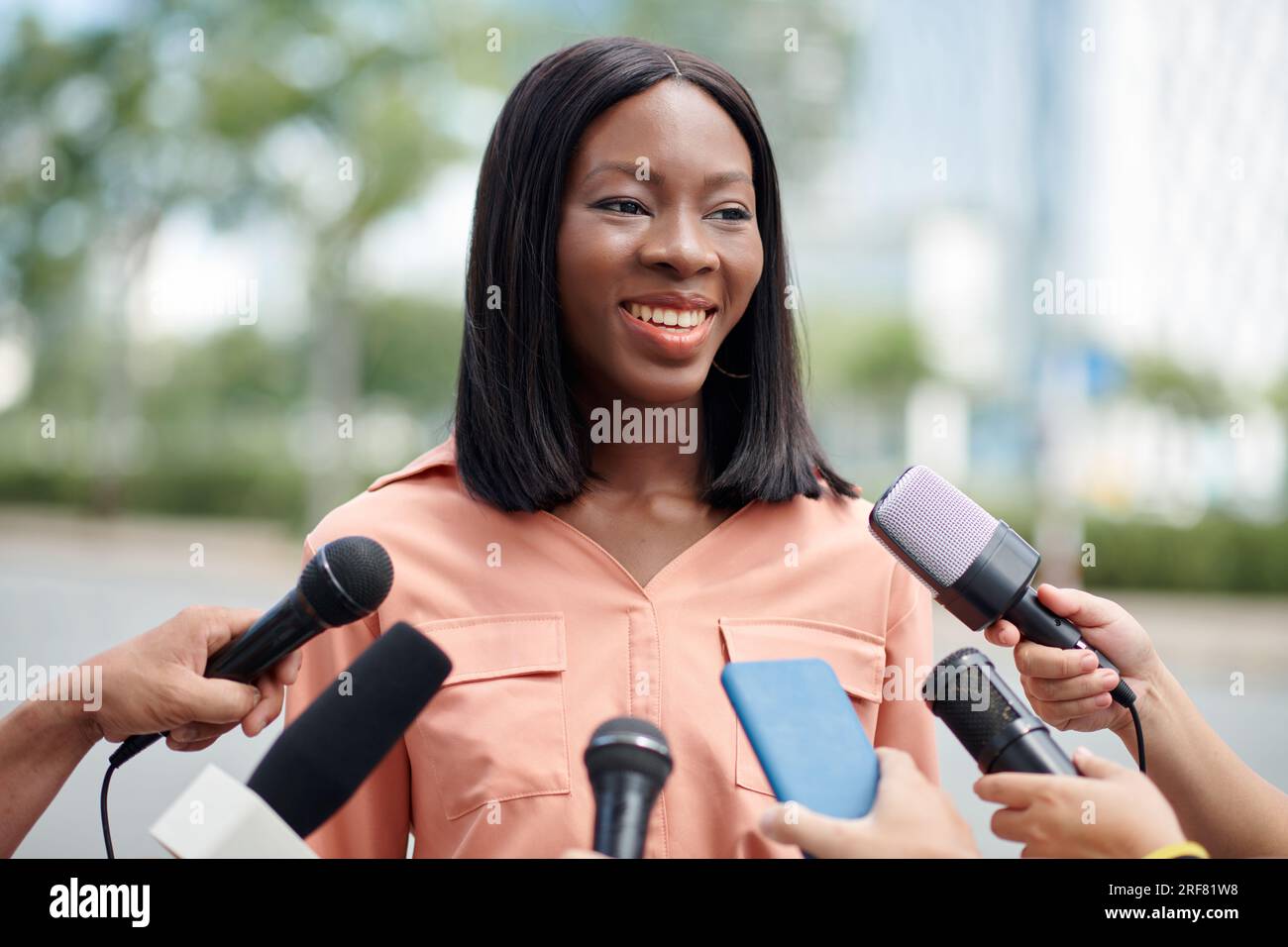 Smiling Black woman giving press conference to journalists from various ...