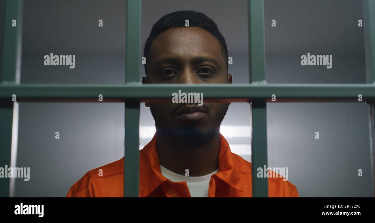 African American man in orange uniform keeps hands in handcuffs on jail ...
