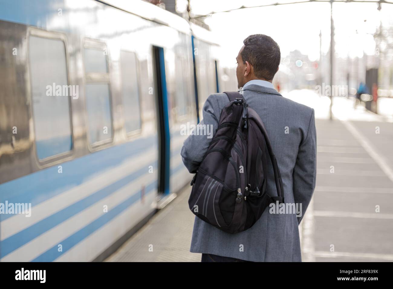 Latino man with suit and backpack taking the train seen from behind ...