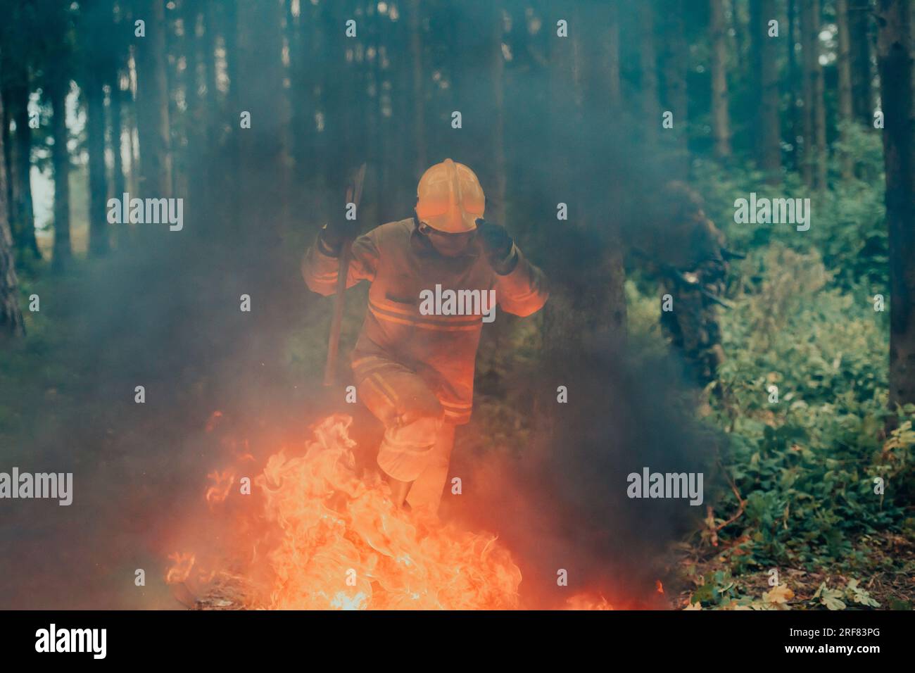 firefighter hero in action danger jumping over fire flame to rescue and ...