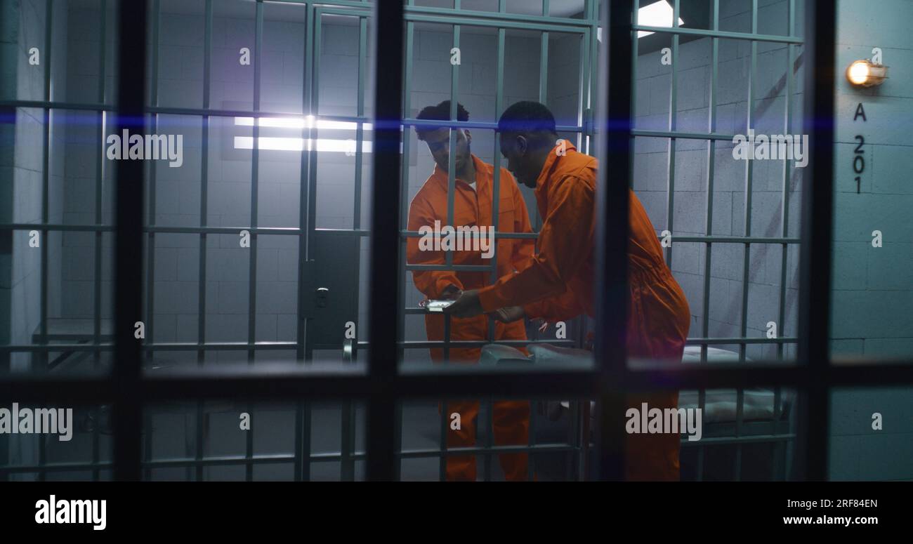 Man in orange uniform gives food from serving trolley to prisoner in ...