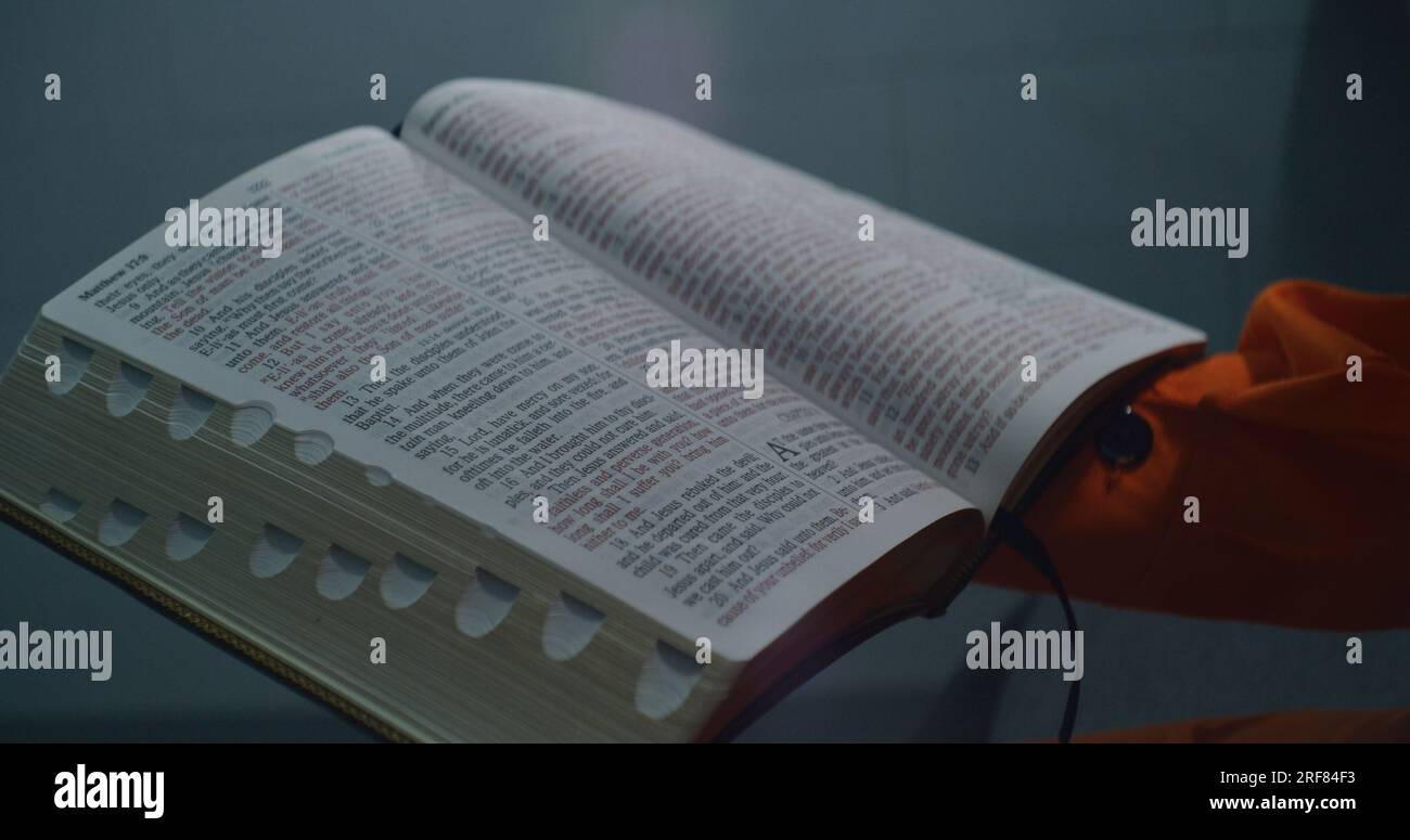 African American prisoner in orange uniform reads Bible in prison cell ...