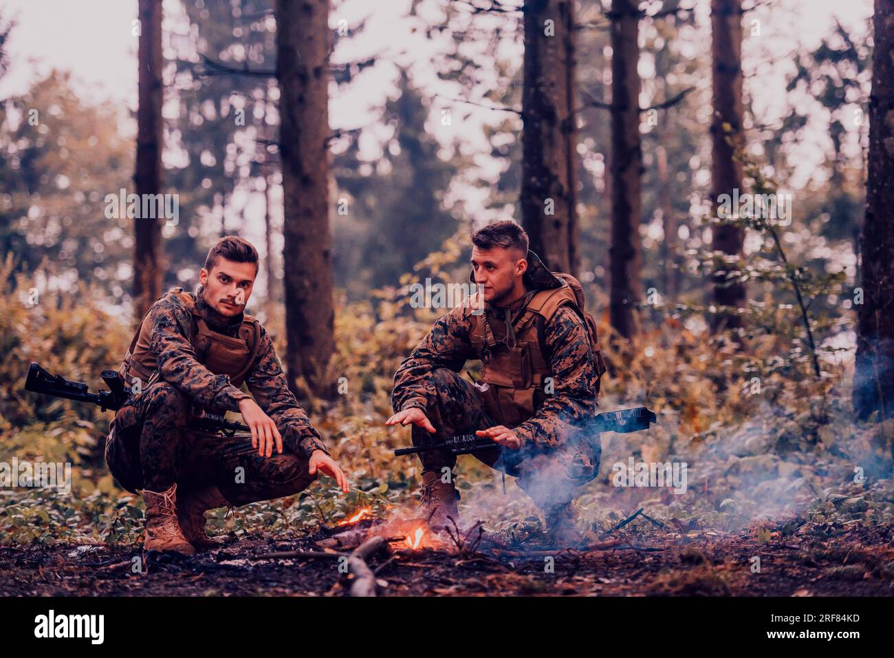 Two exhausted soldiers sitting by the fire after a weary and heavy war ...