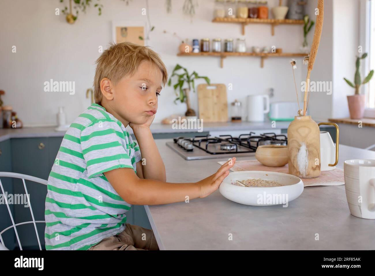 Beautiful blond child, boy, refusing to eat cereal for breakfast at ...