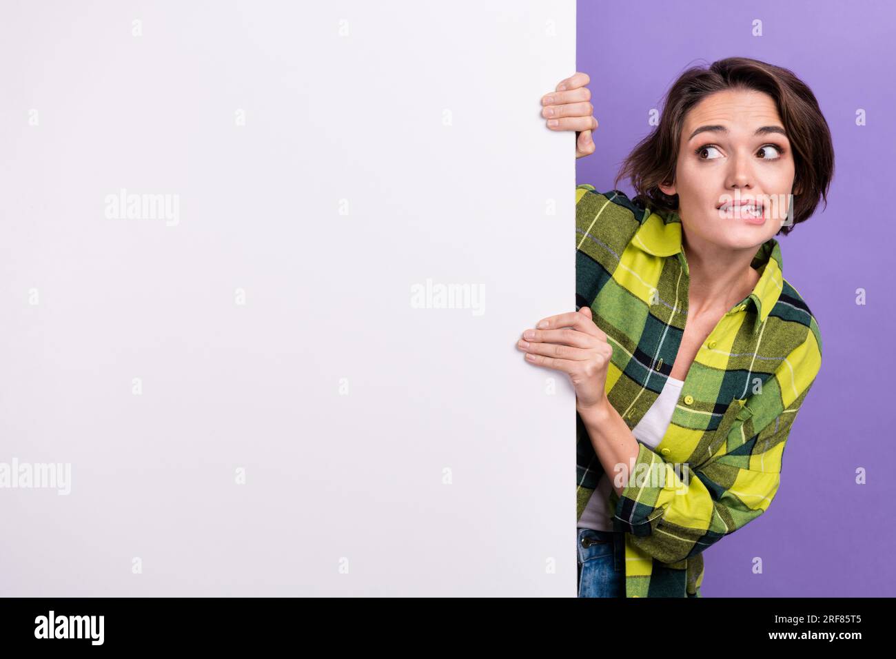 Photo of young woman bite lips look interested nervous hiding behind ...