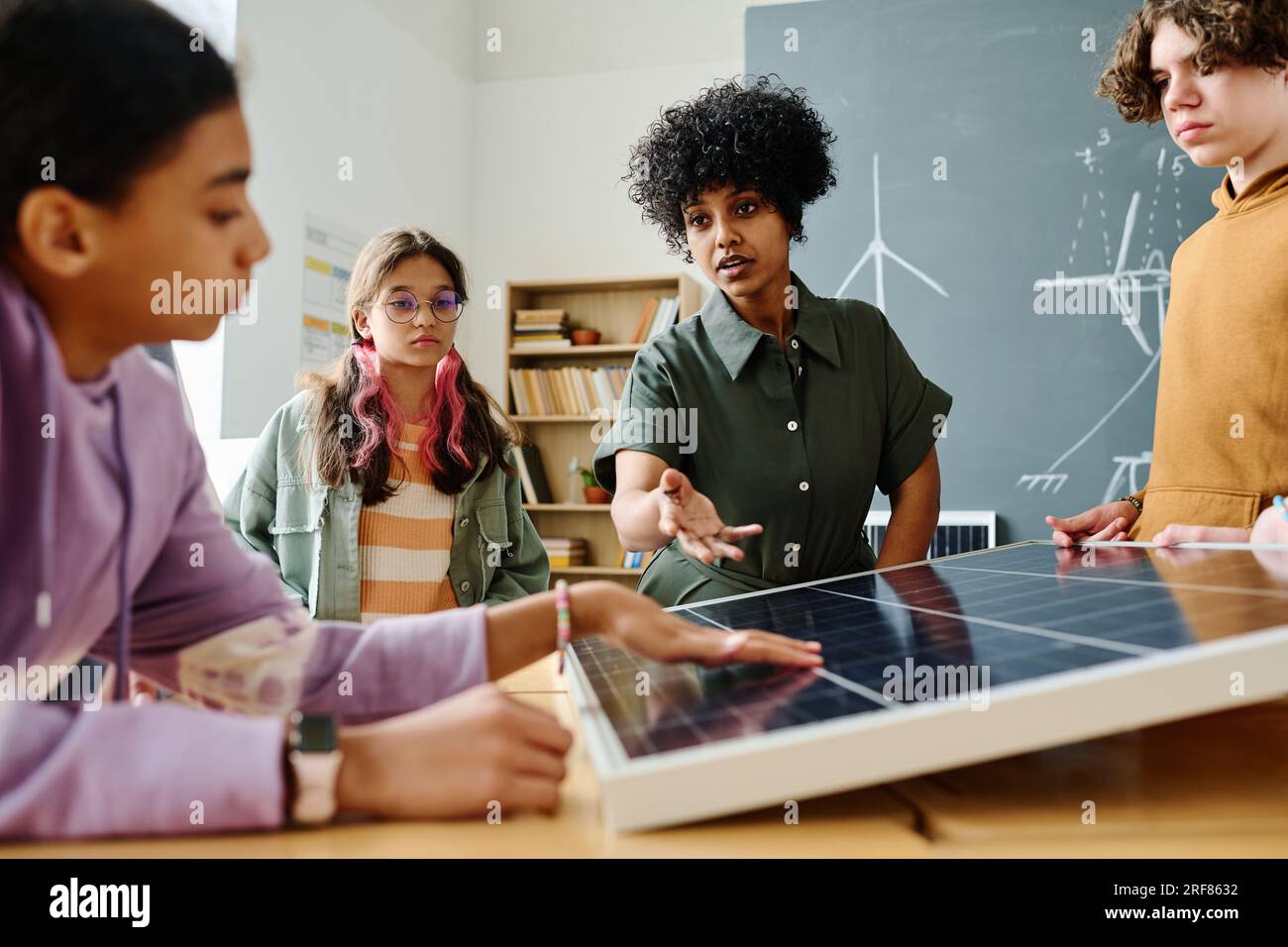 Teacher explaining the work of solar panel to students during lesson at ...