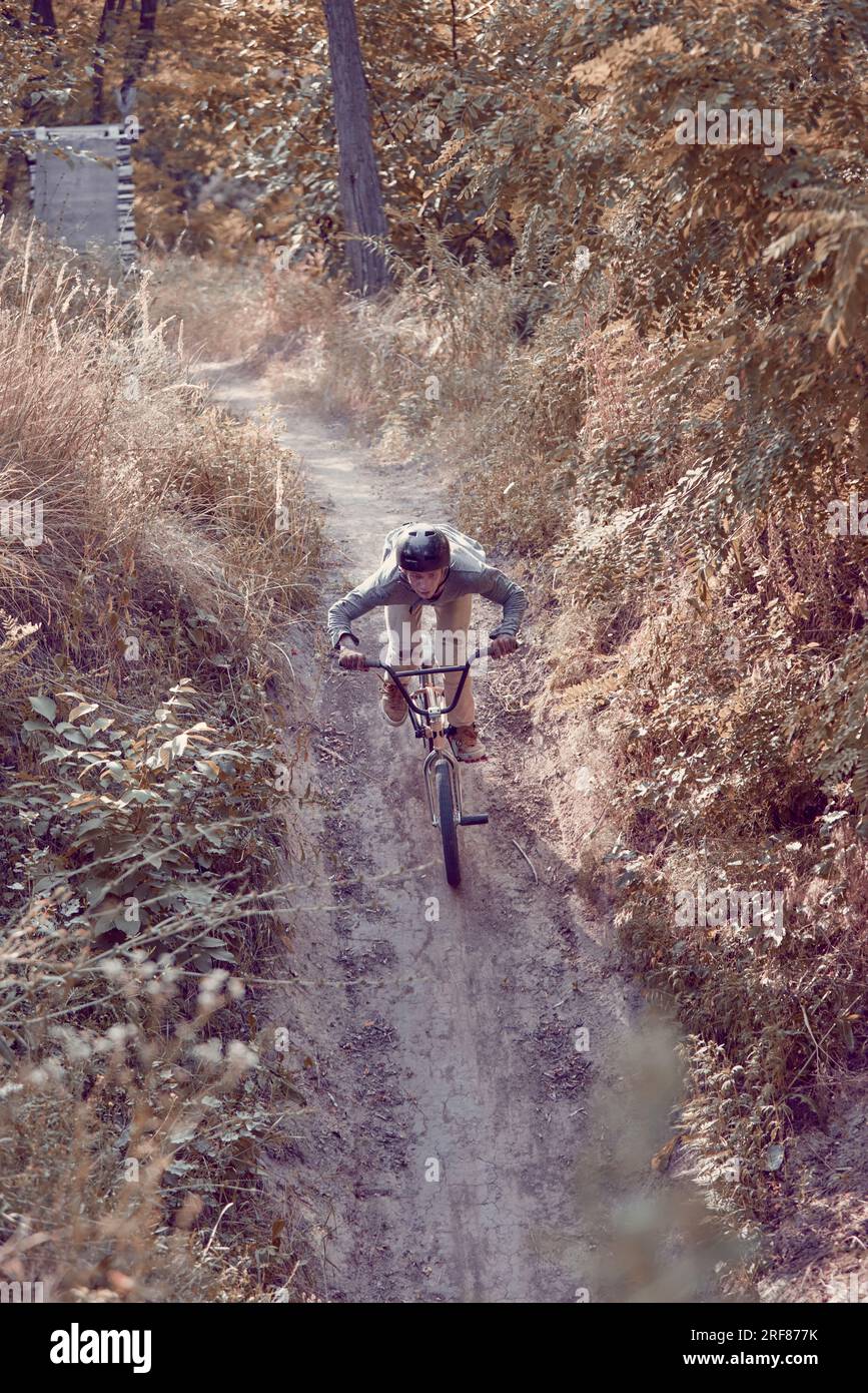 Developing speed during ride. Young man riding on bmx bike in forest ...