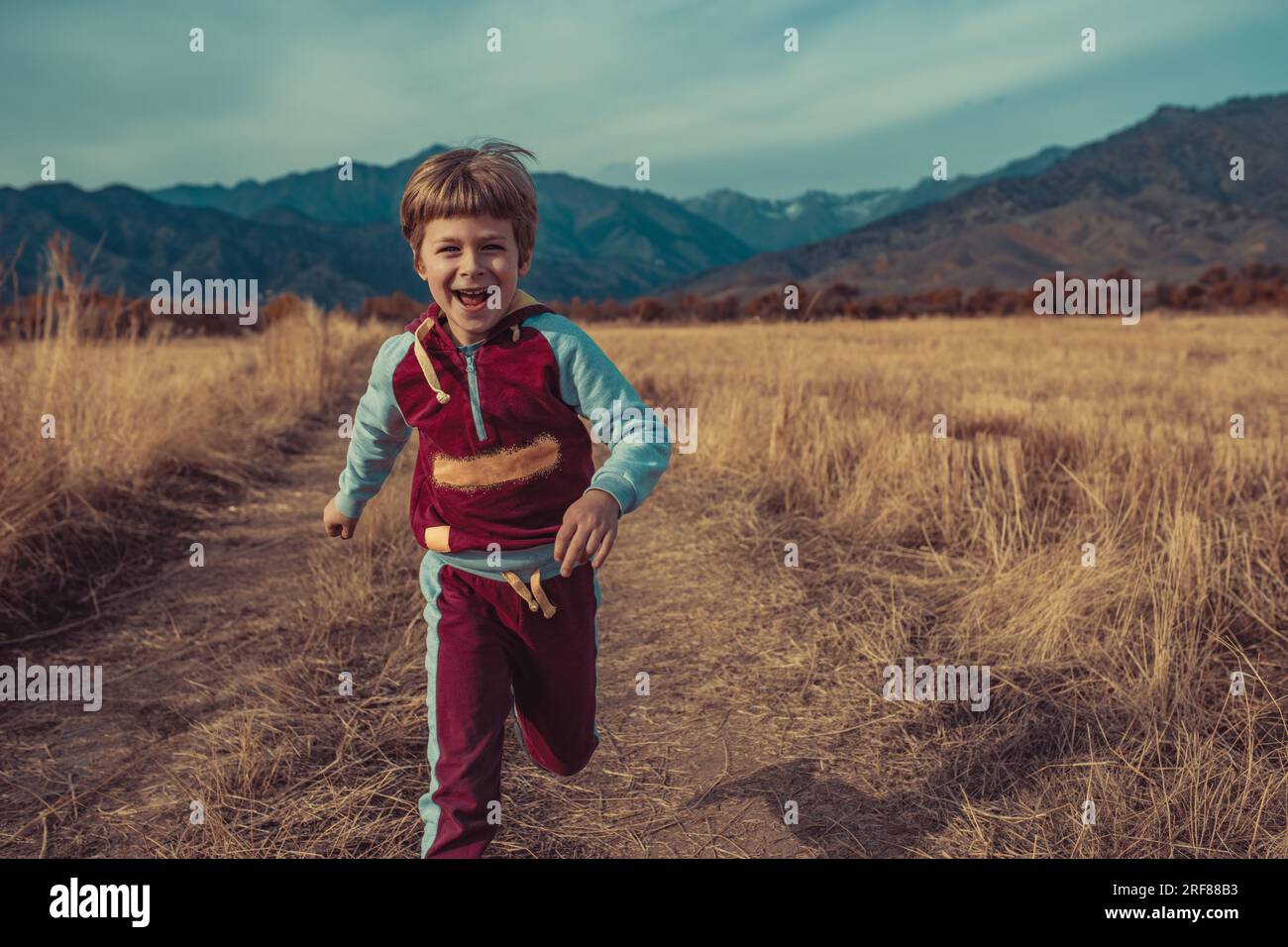 Child running on autumn field on mountains background Stock Photo - Alamy