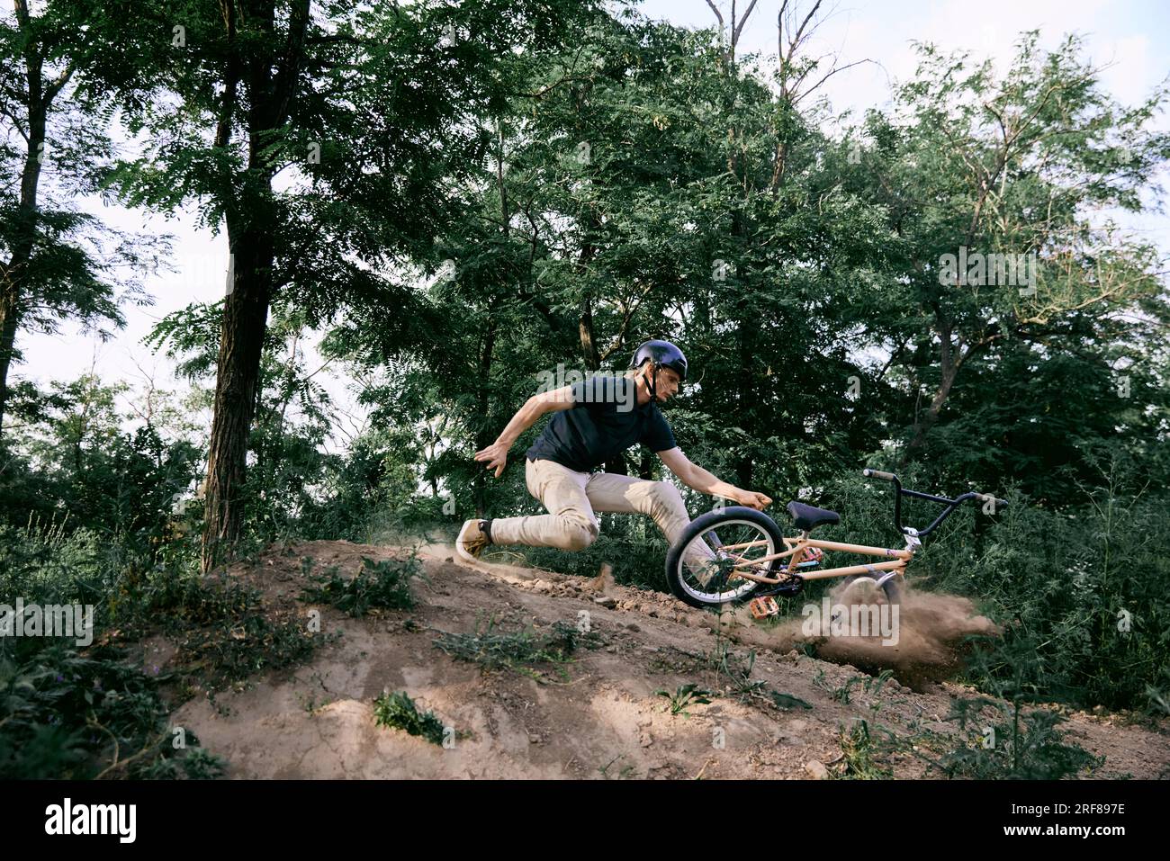 Young man in helmet riding bmx bike in forest, doing dangerous tricks ...