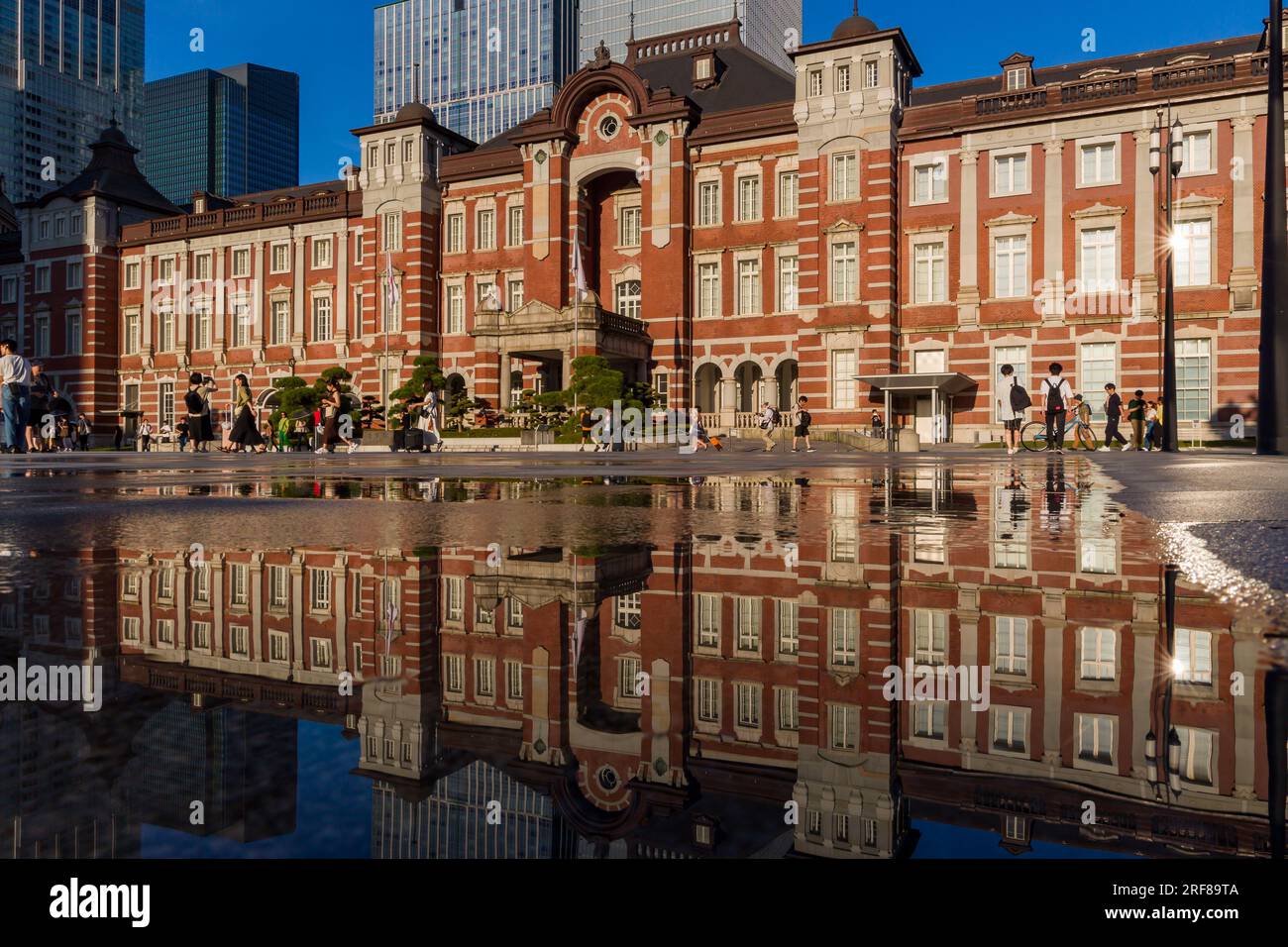 TOKYO, JAPAN - JULY 30 2023: Tokyo Station reflected in water sprayed ...