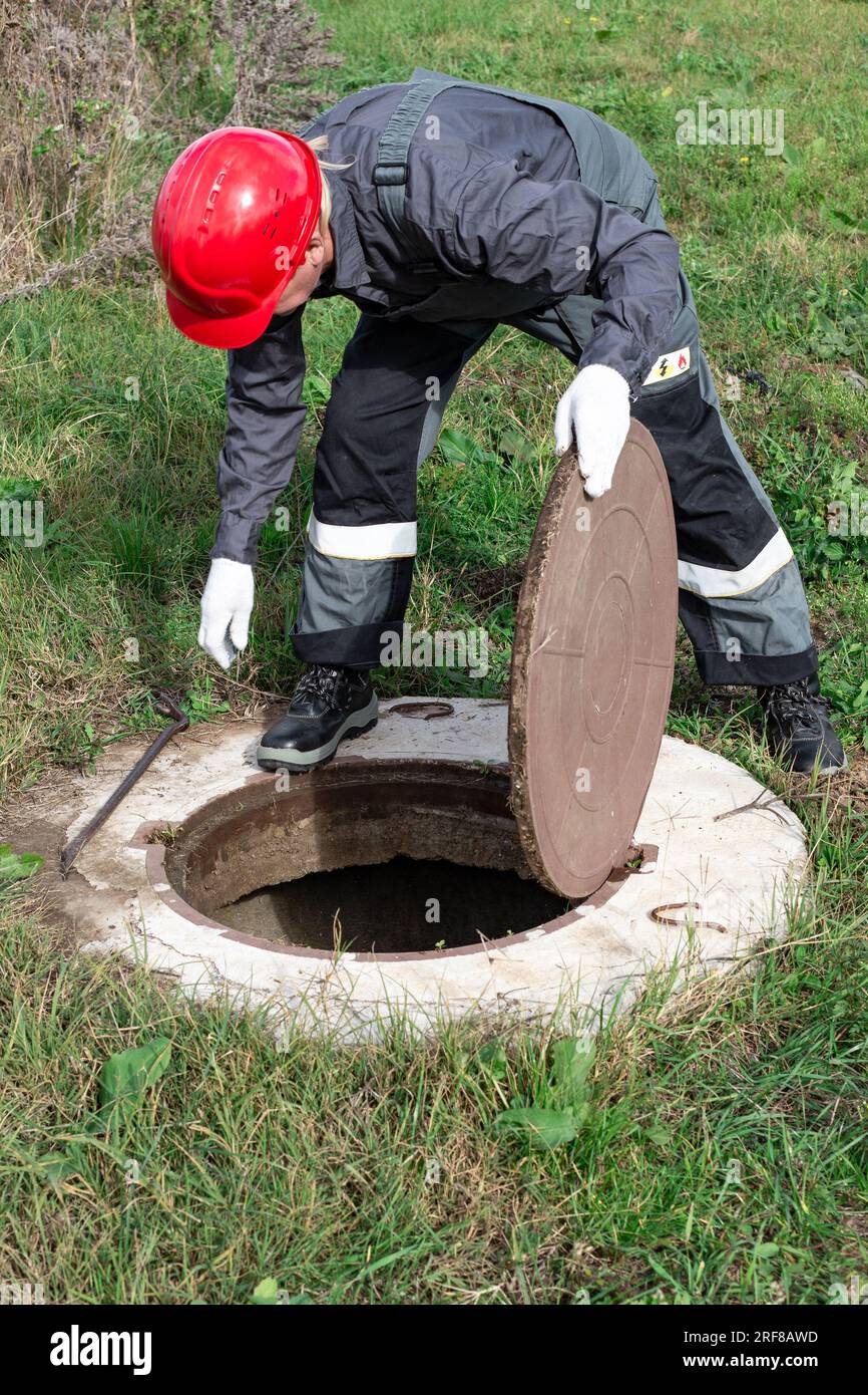 The communal worker opened the sewer hatch and looks inside. Inspection ...