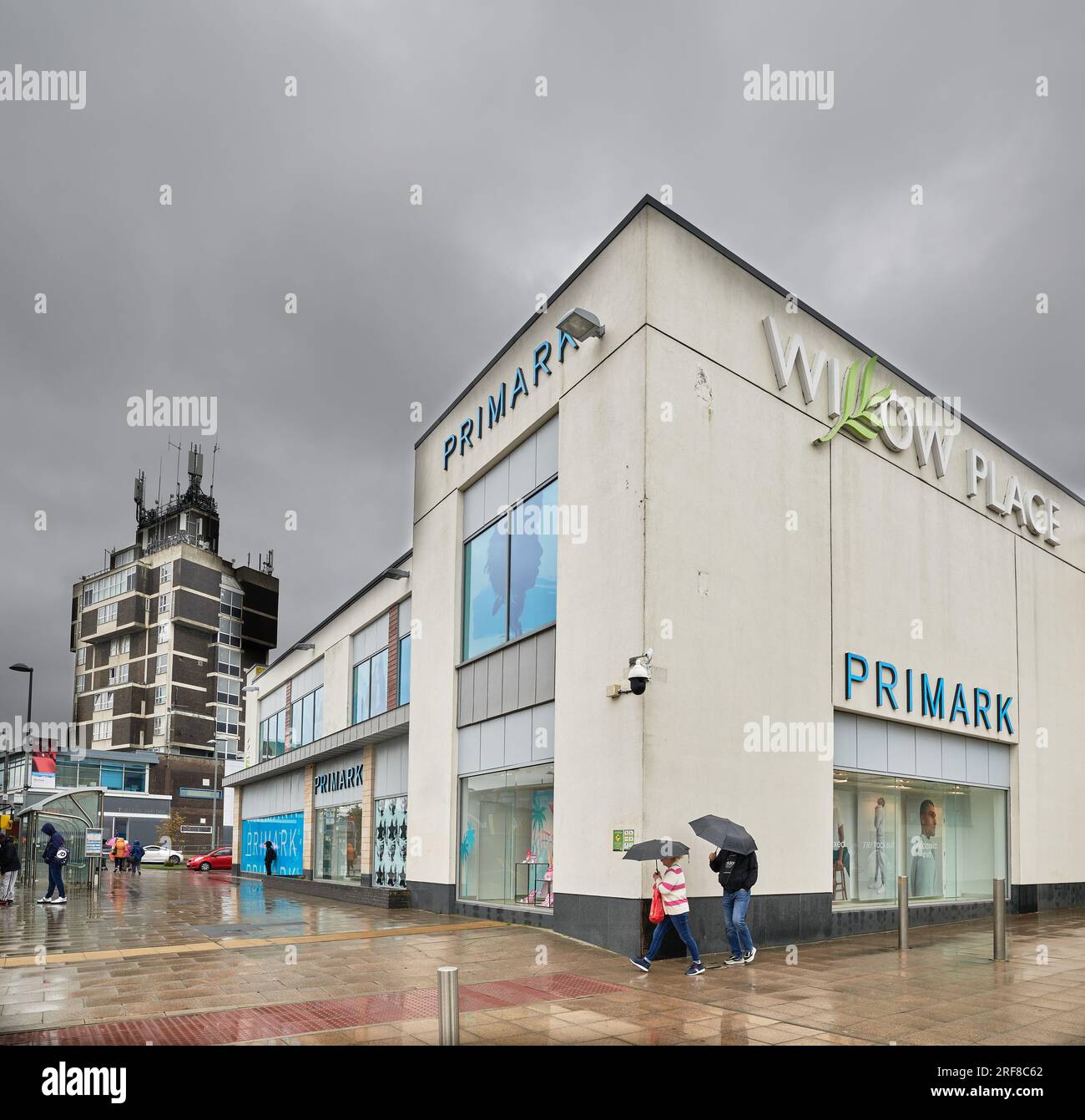 Two shoppers with umbrellas pass Primark shop at the town centre of ...