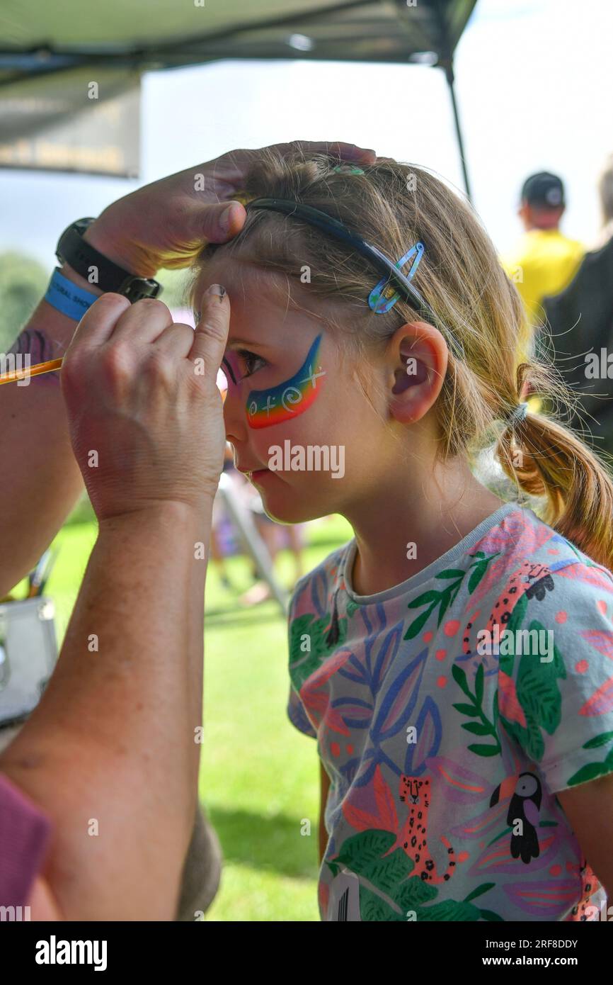 Child having their face painted at country fair, Hampshire, England ...