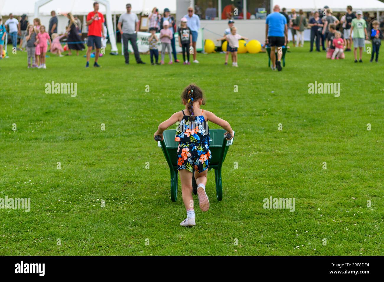 Girl pushing a wheelbarrow during wheelbarrow racing at a country fair ...