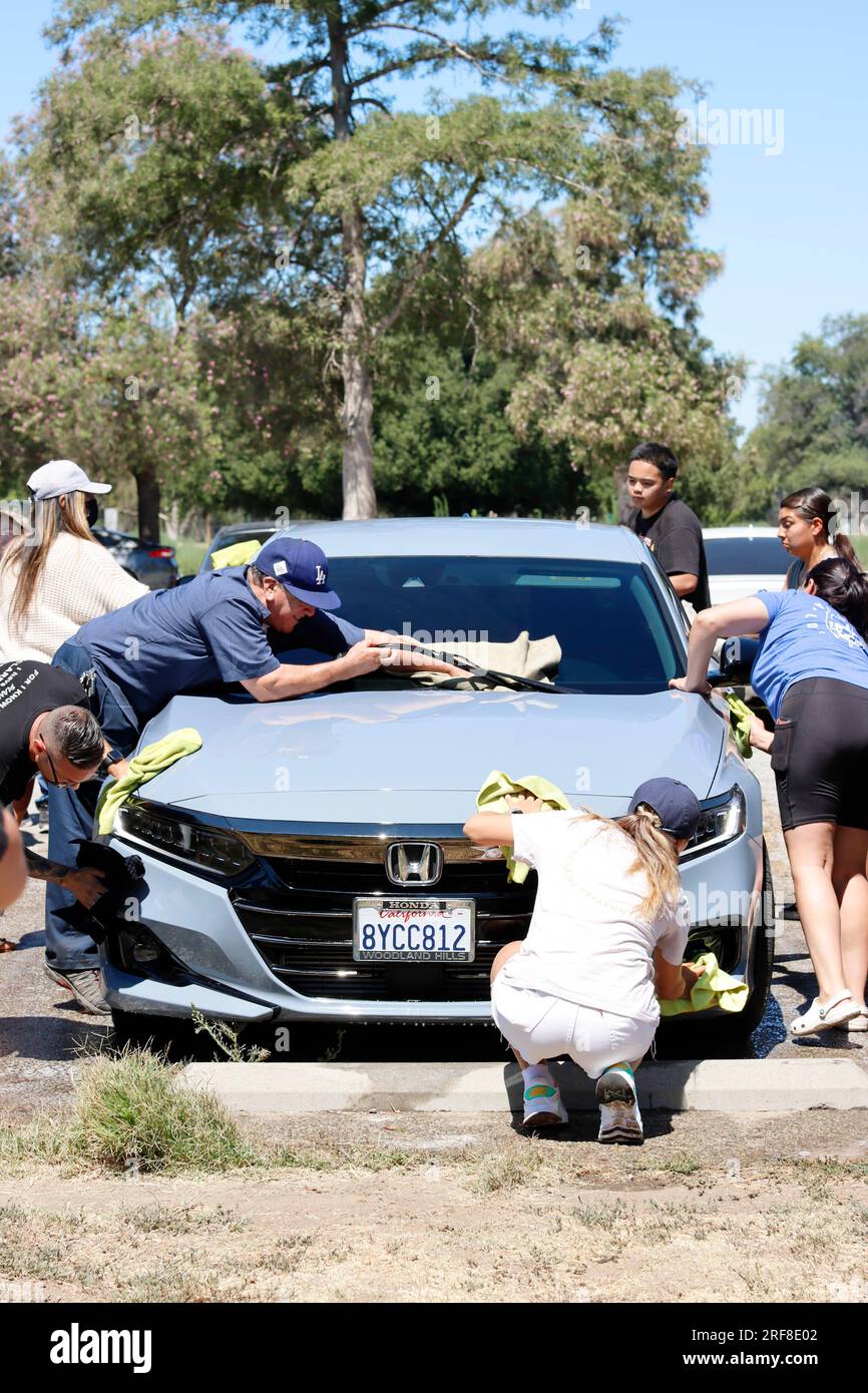 Volunteers wash a car at a fundraiser for the families of car crash ...